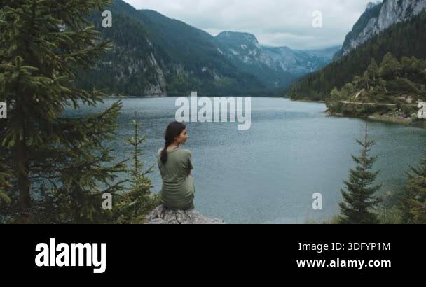 Young woman sitting on cliff in front of Breathtaking background. Girl ...