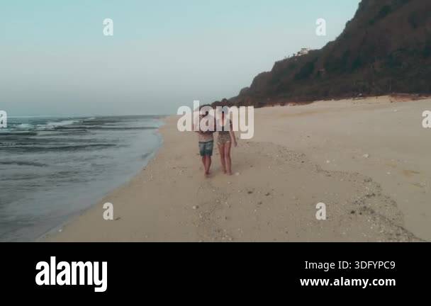 Portrait of beautiful girl and young man walking on the beach, drone ...