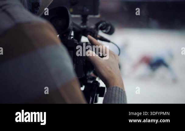 Close-up on cameraman shooting ice hockey game. Camera operator ...