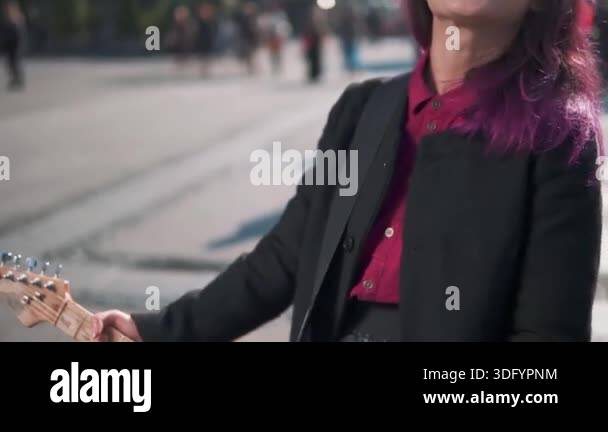 Daring rebel woman portrait with purple hair playing electric guitar at ...