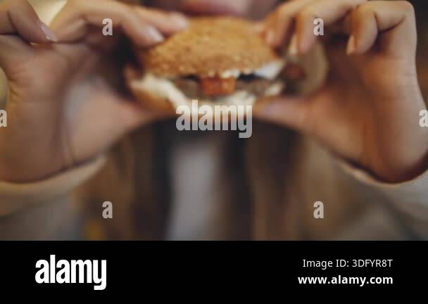 Macro close up of Young woman eating burger in fast food restaurant ...