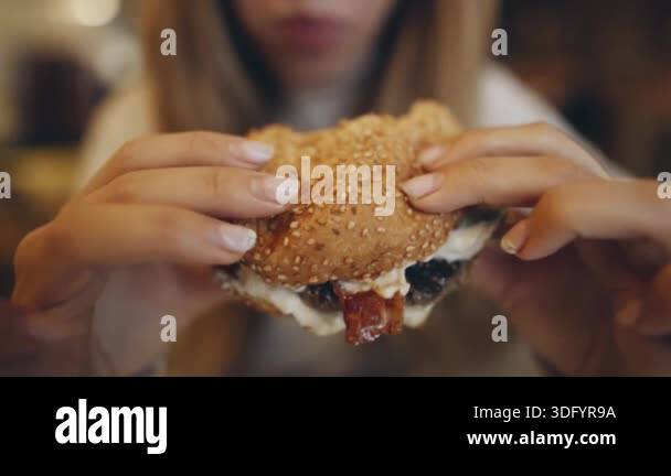 Macro close up of Young woman eating burger in fast food restaurant ...