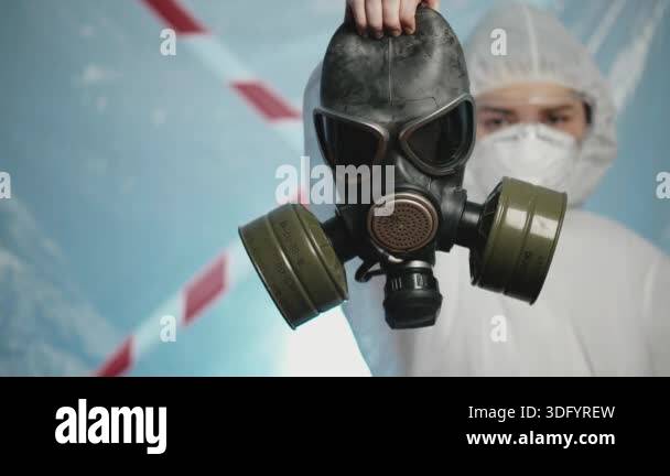 Female doctor virologist in a protection suit and respirator holds a ...