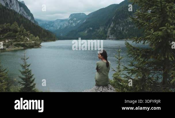 Young woman sitting on cliff in front of Breathtaking background. Girl ...