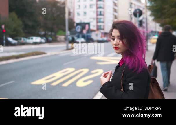 Pretty asian hipster girl waiting at a bus stop on a busy street. Woman ...