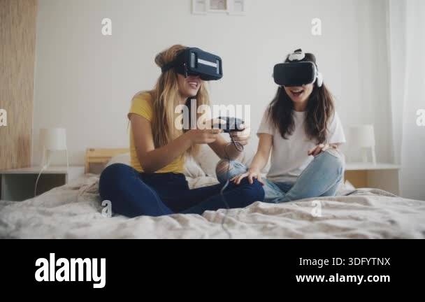 Exited girls in VR helmets at home. Two women in virtual reality ...