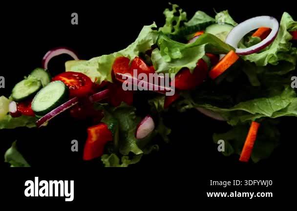 Mix of different fresh vegetables shaking and flying up on the black ...
