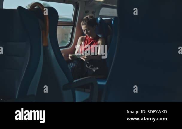 Young asian girl sitting in subway or train, watching at tickets or ...