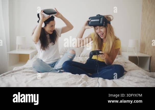 Two women put off virtual reality headsets while sitting on bed, share ...