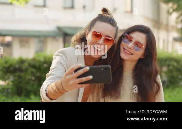Pretty stylish girls on street background. Two young smiling hipster ...
