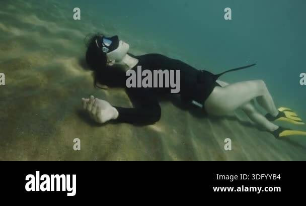 Diver woman lying underwater bottom, filmed on cinema camera. Brutal ...