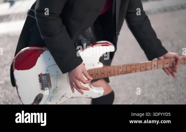 Daring rebel woman with purple hair playing electric guitar at city ...