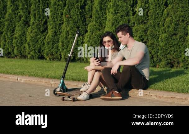 Guy and girl with scooter and skateboard with removed protective mask ...