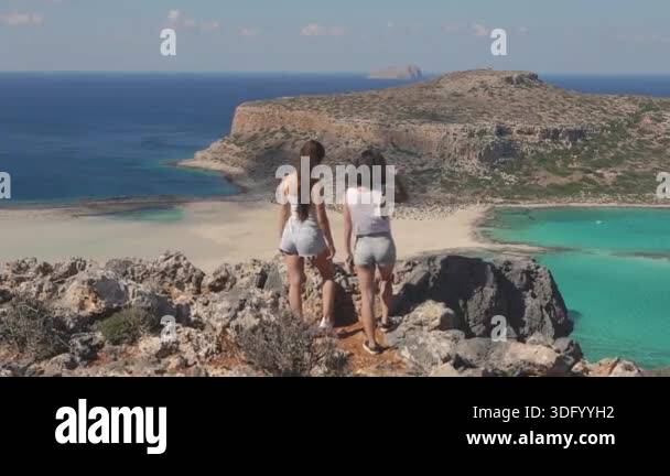 Two beautiful girls standing on edge of cliff. Female friends admire ...