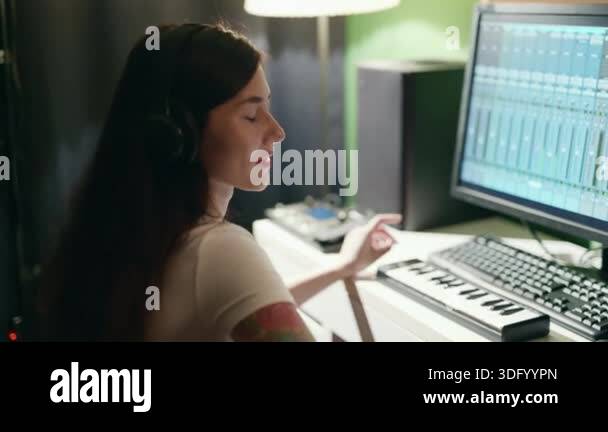 Young woman playing guitar and synthesizer creating music using ...