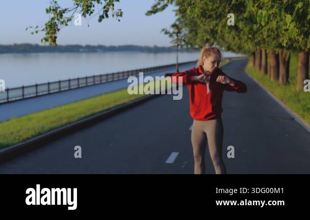 Young blonde girl in sportswear doing exercises or workout to warm up ...