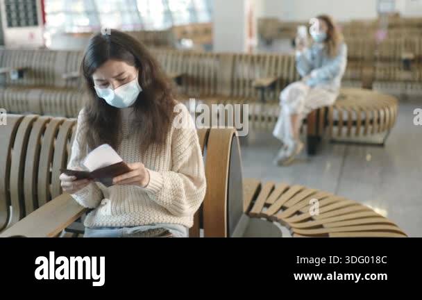 Young woman wearing medical mask sitting alone in airport terminal and ...