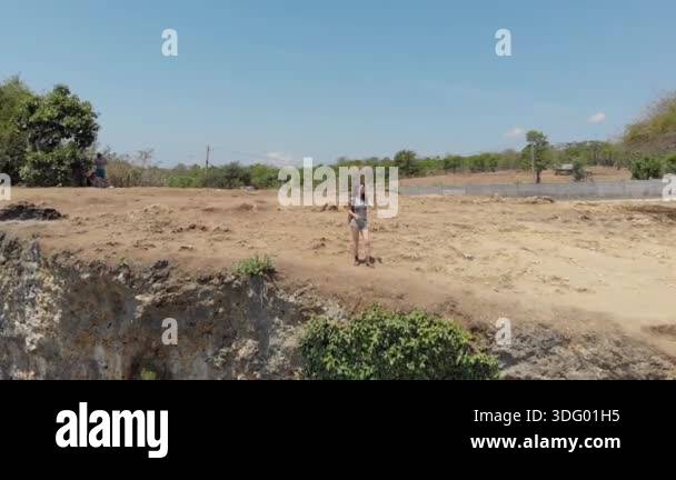 Alex Drone shot of woman facing edge of cliff in savannah background ...