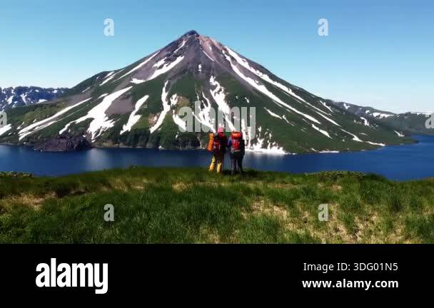 Couple tourists walking on krenitsyn volcano on the Kuril islands ...