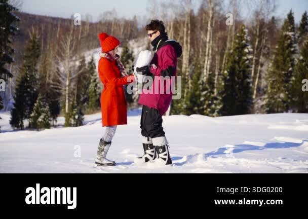 Man presenting a heart shape made of snow to his girlfriend. Happy ...