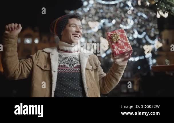 Portrait of happy guy dancing in a middle of a square during holiday ...