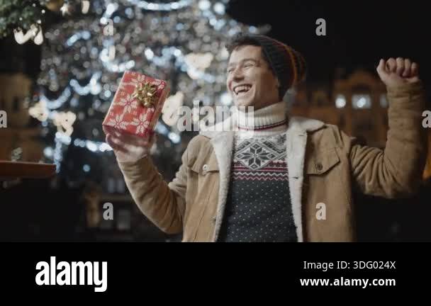 Happy man with a xmas gift dancing at old town square. Christmas, new ...