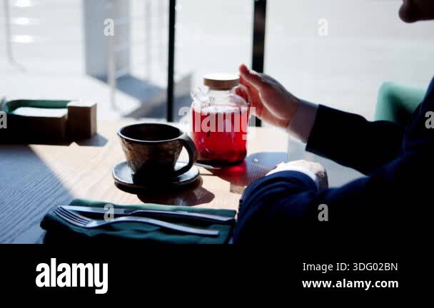 Close-up shot of cafe visitor pouring tea from teapot to beautiful ...