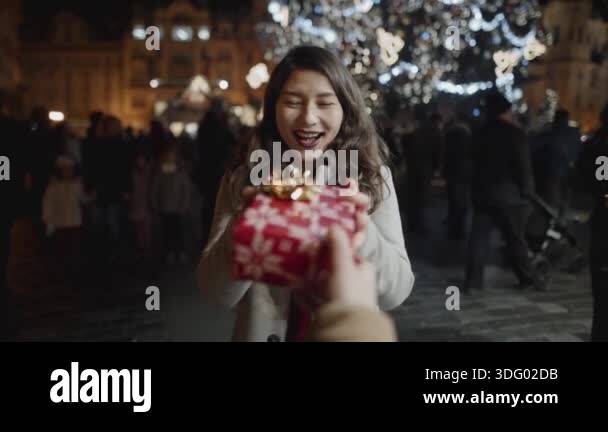 Portrait of beautiful girl receiving present from cameraman. Young ...