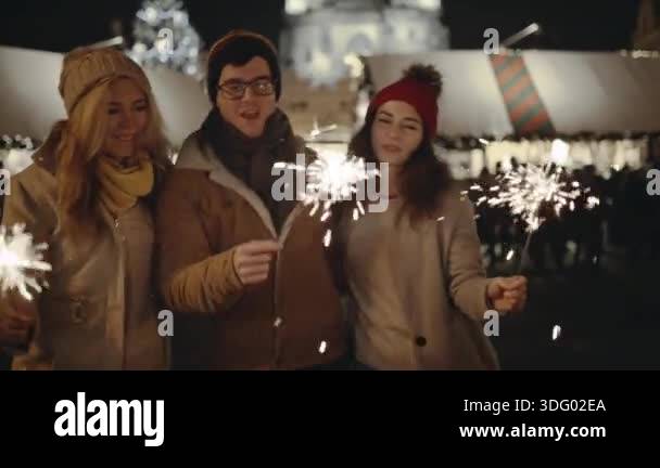 Happy friends smiling and dancing with bengal lights in the streets of ...