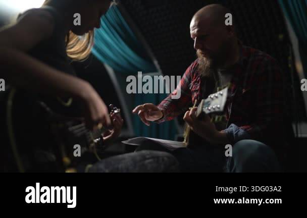 young beautiful girl in lesson with experienced guitarist in studio ...