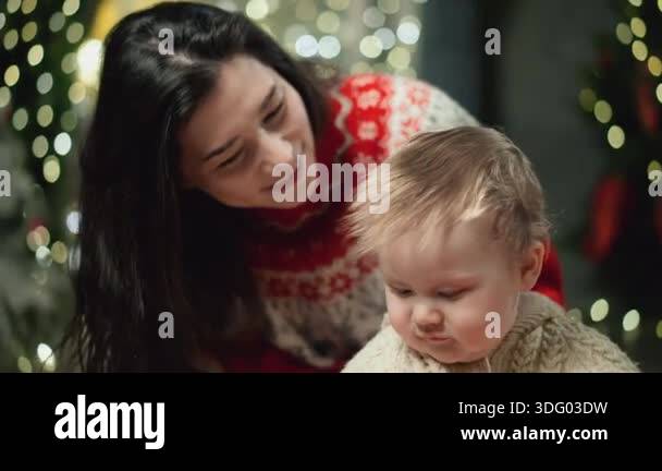 Mom and baby are looking at a red Christmas hat. Family Spending Winter ...