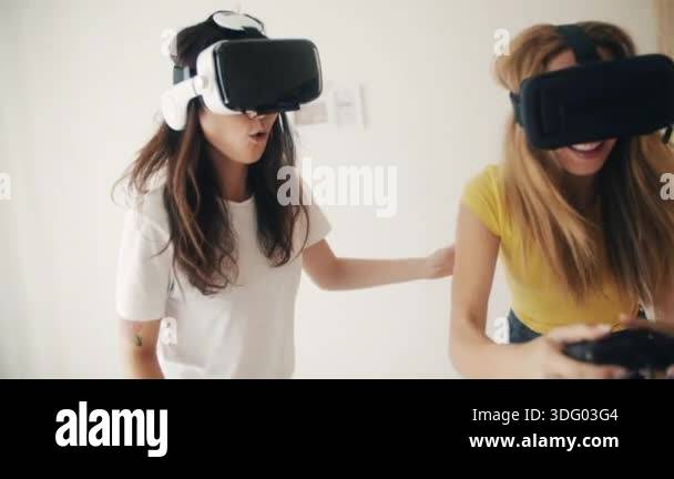 Exited girls in VR helmets at home. Two women in virtual reality ...