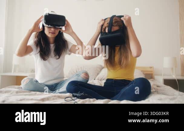 Exited girls in VR helmets at home. Two women in virtual reality ...