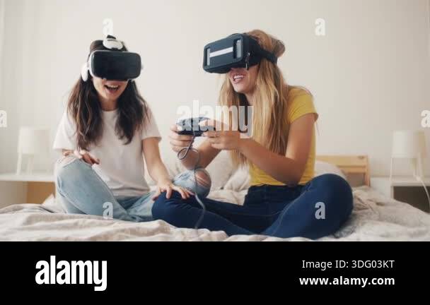 Exited girls in VR helmets at home. Two women in virtual reality ...