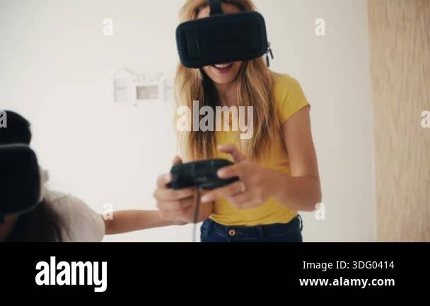Exited girls in VR helmets at home. Two women in virtual reality ...