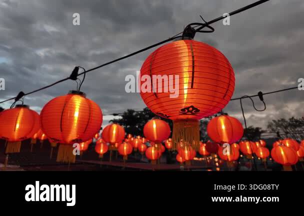 A bunch of red lanterns hanging from wires. Some of them are lit up ...