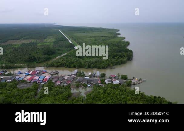 A river runs through a oil palm and a small village is on the other ...