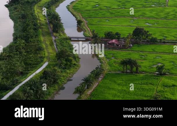 River runs through a lush green field with a house on the right side ...
