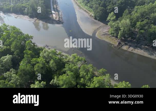A river with a bridge over it. The water is brown. Trees are on both ...