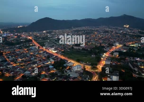 A city at night with a mountain in the background. The city is lit up ...