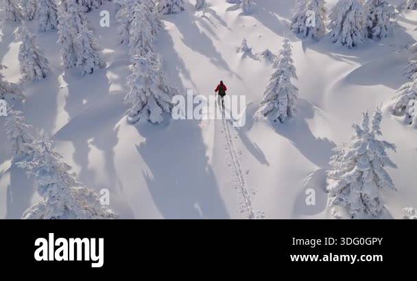 Smooth cinematic flight over a snow-covered alpine landscape with a ski ...