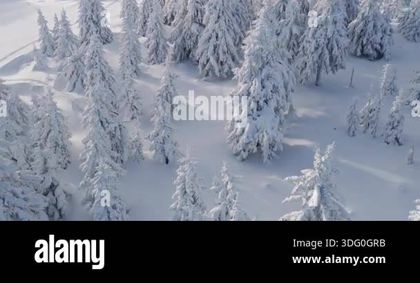 Smooth cinematic flight over a snow-covered alpine landscape with a ski ...