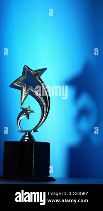 Silver shooting star trophy on black base rotating against a solid blue ...