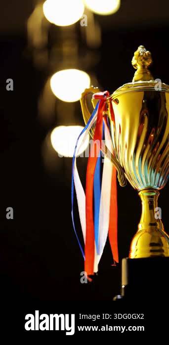 Vertical shot of golden trophy cup with red white and blue ribbons ...
