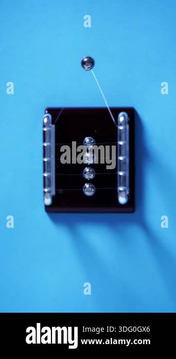 Top down view of hand operating Newton's cradle on blue background ...
