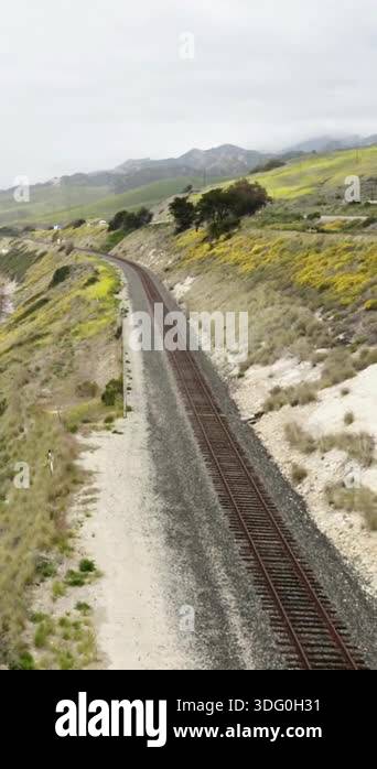 Aerial view of single train track running along coastal hillside with ...