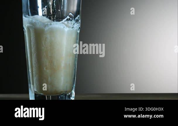 A clear glass is filled with a carbonated light colored beverage like ...