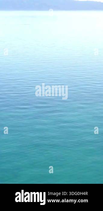 Aerial view flying low over calm turquoise blue ocean water surface ...