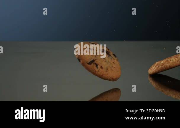 A variety of round cookies fall from the air and bounce across a dark ...