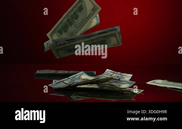 Multiple hundred dollar bills fall from the top of the frame and land ...